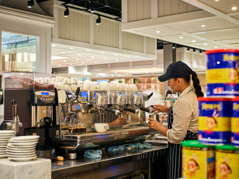 cafe worker preparing coffee with coffee machines and coffee in background